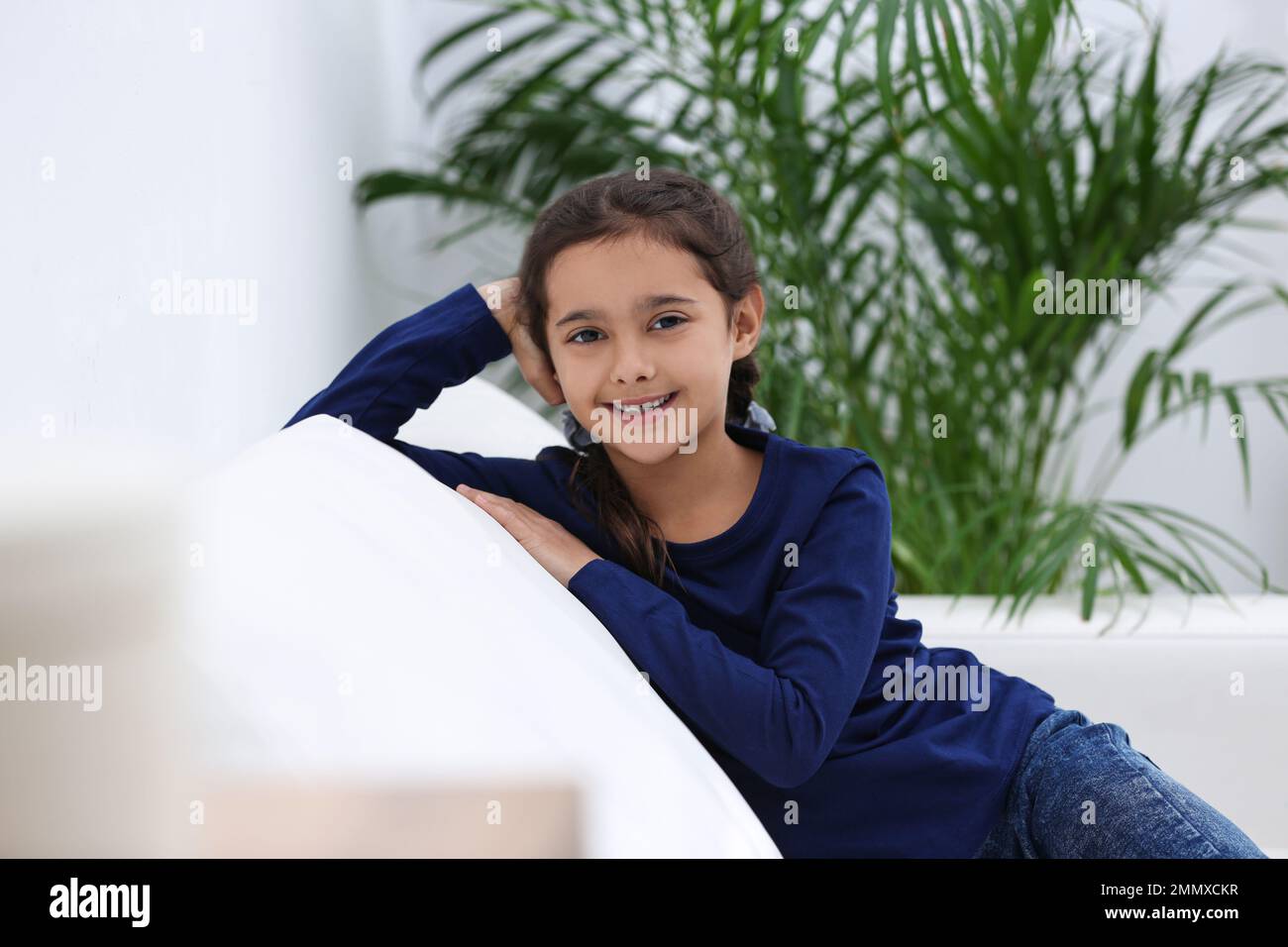 Cute little girl on sofa in living room Stock Photo - Alamy