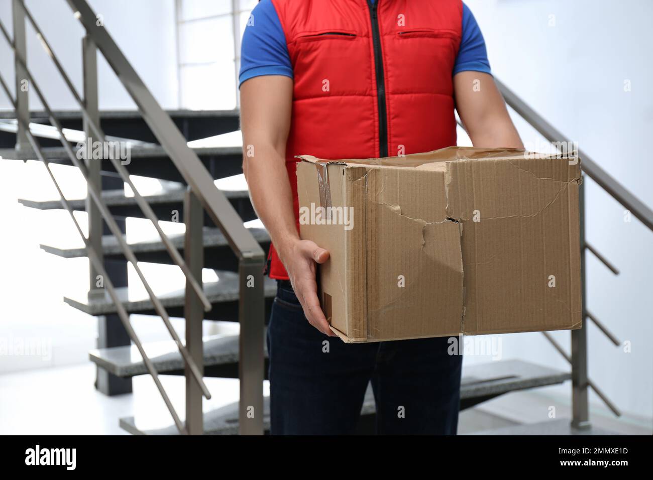 Courier with damaged cardboard box indoors, closeup. Poor quality ...