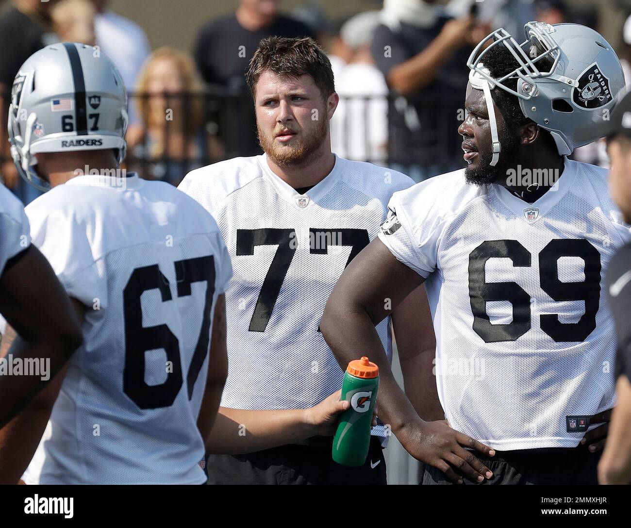 Oakland Raiders' Kolton Miller (77) walks on the field between Ian ...