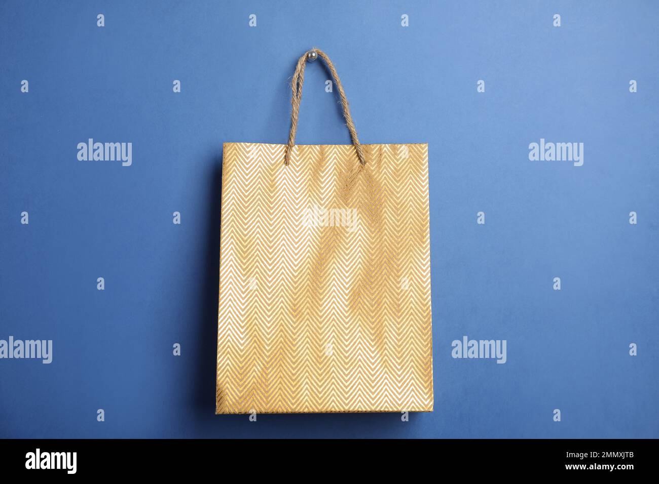 Gold shopping paper bag on blue background Stock Photo - Alamy