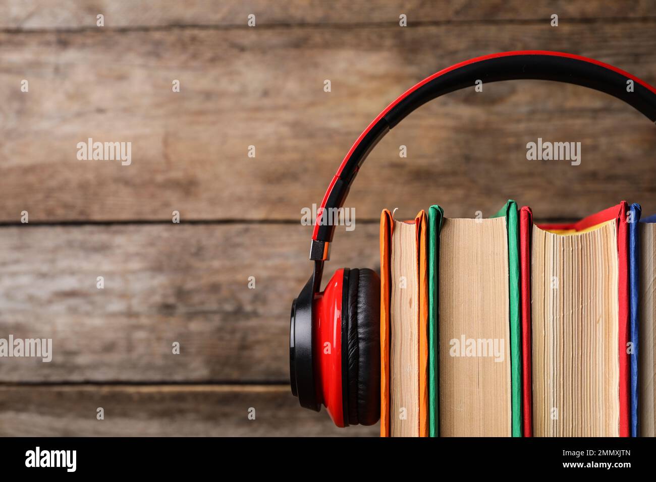 Books and modern headphones on wooden background, closeup. Space for ...