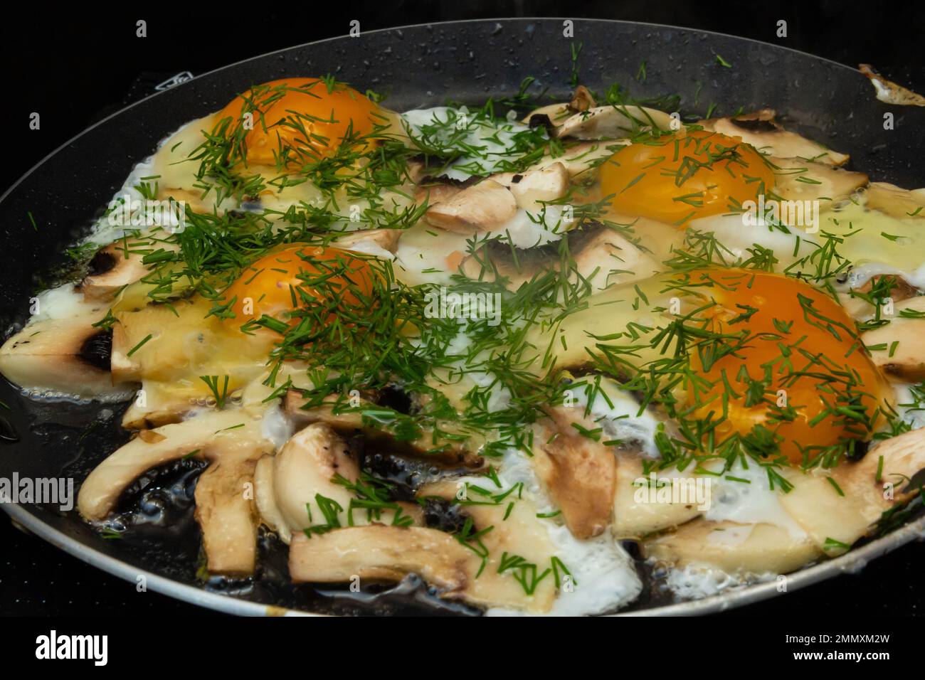 Fried mushrooms and eggs in a pan. The process of cooking breakfast ...