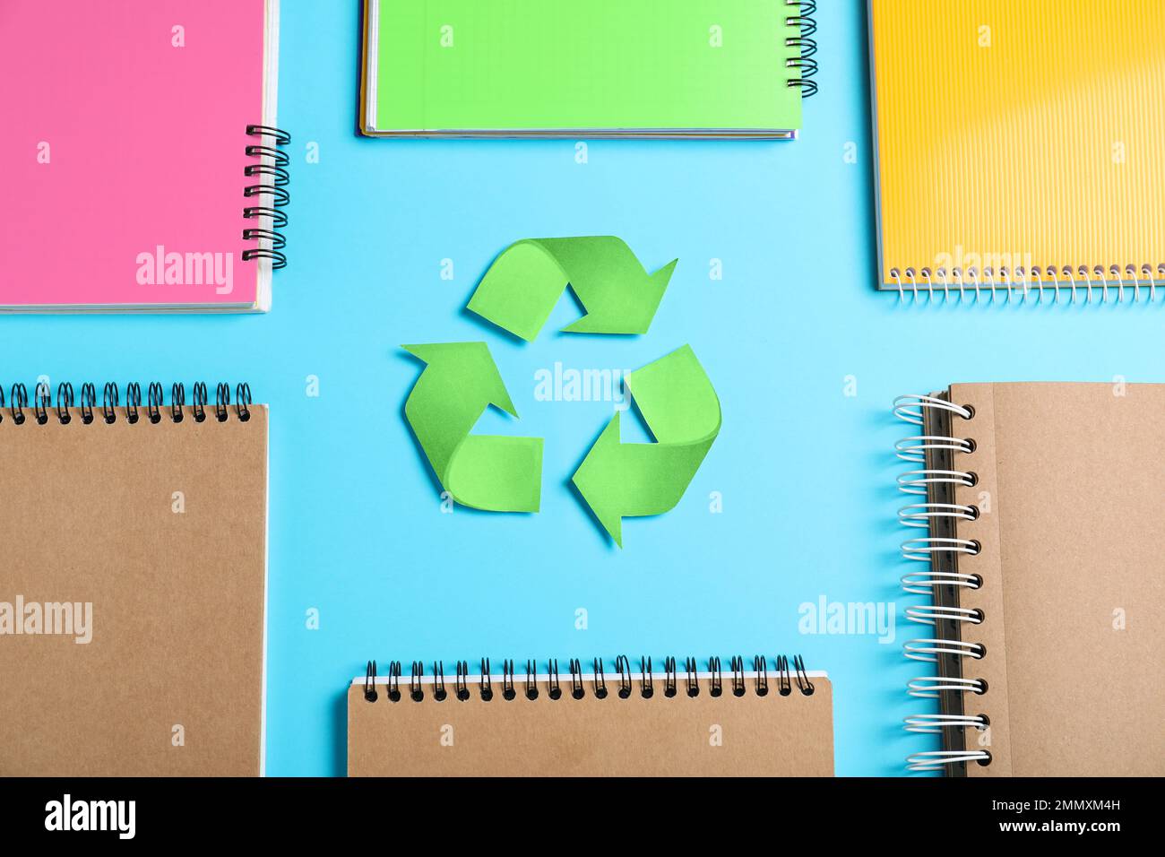 Recycling symbol, plastic and paper notebooks on light blue background ...