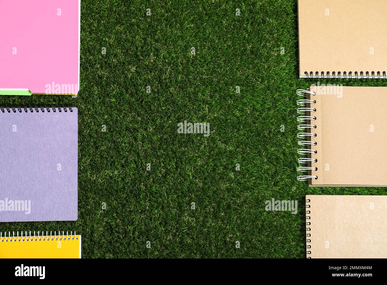 Flat lay composition with plastic and paper notebooks on green grass ...