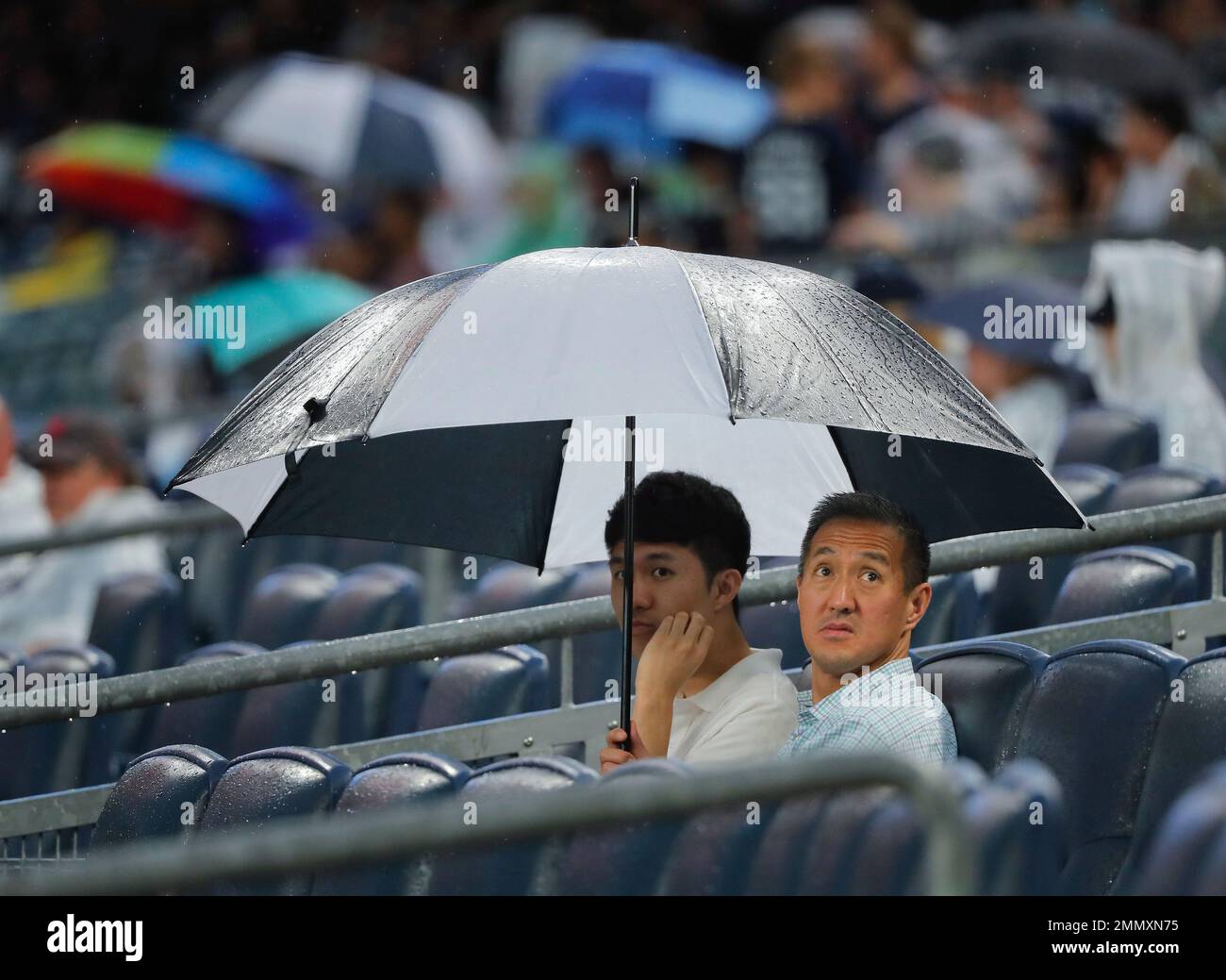 Baseball fans wait out a rain delay before a baseball game between the ...