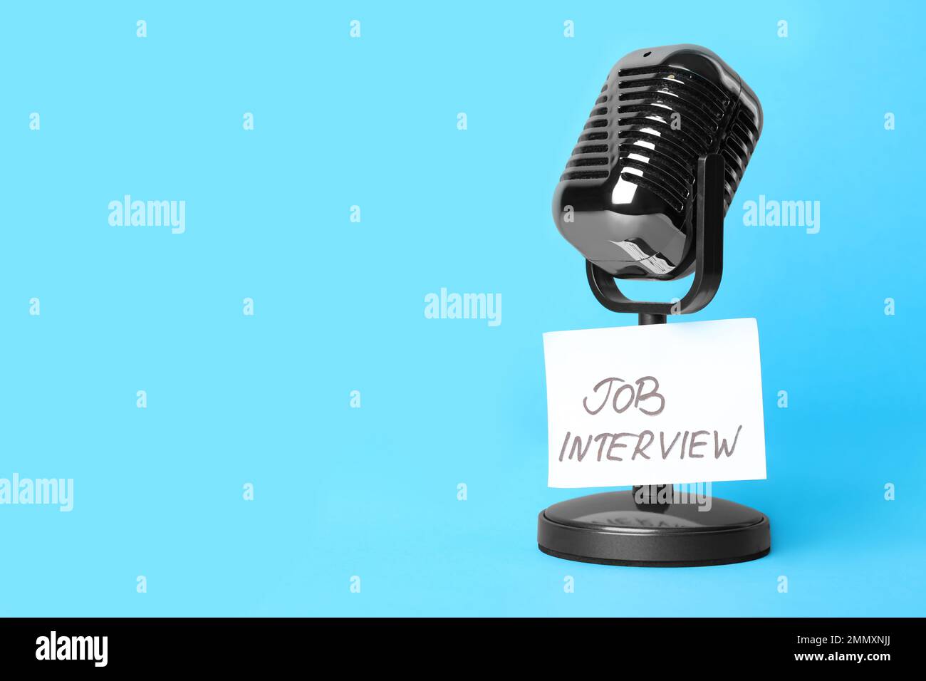 Retro microphone and reminder note with words JOB INTERVIEW on light ...