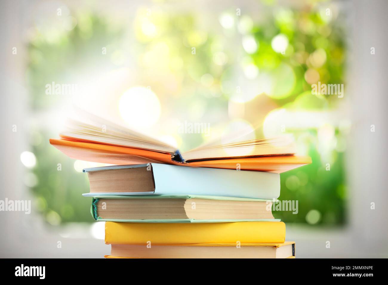 Stack of colorful books on blurred green background Stock Photo - Alamy
