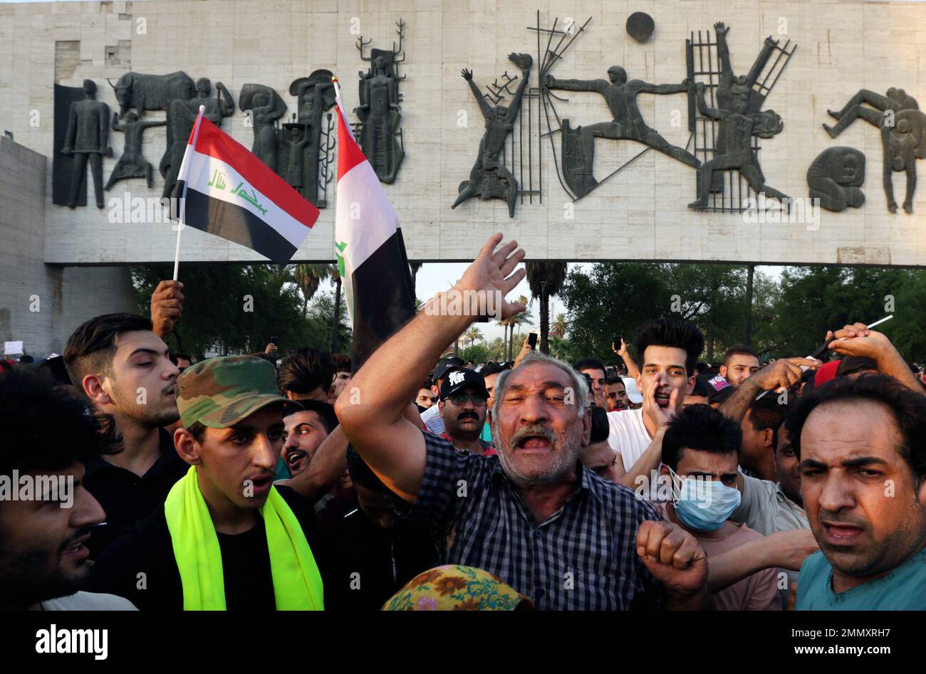 Iraqi protesters wave national flags and chant slogans demanding ...