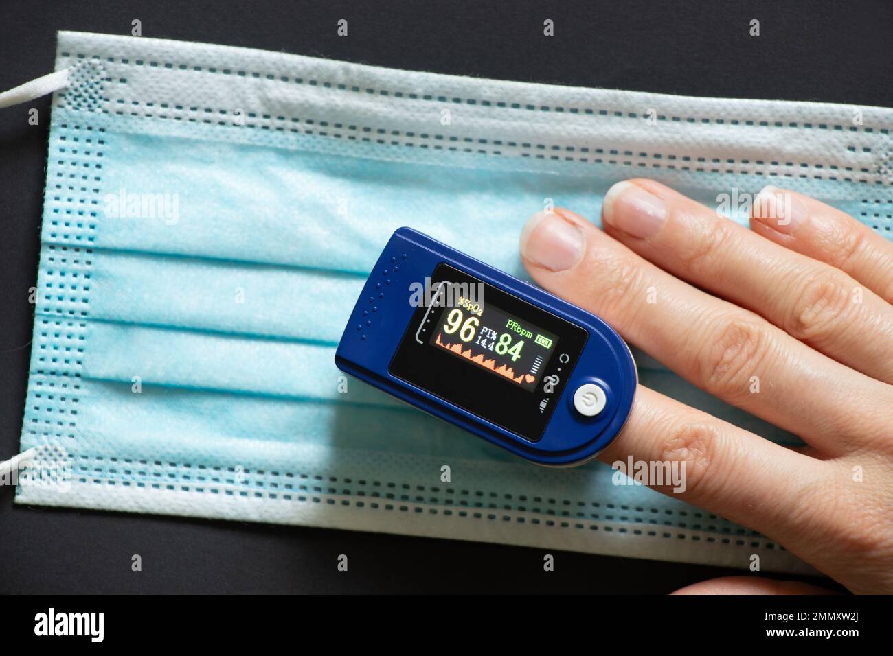 woman's finger pulse oximeter and disposable medical mask on isolated ...