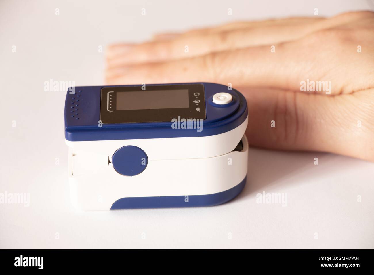 pulse oximeter on the finger of a woman on an isolated background ...