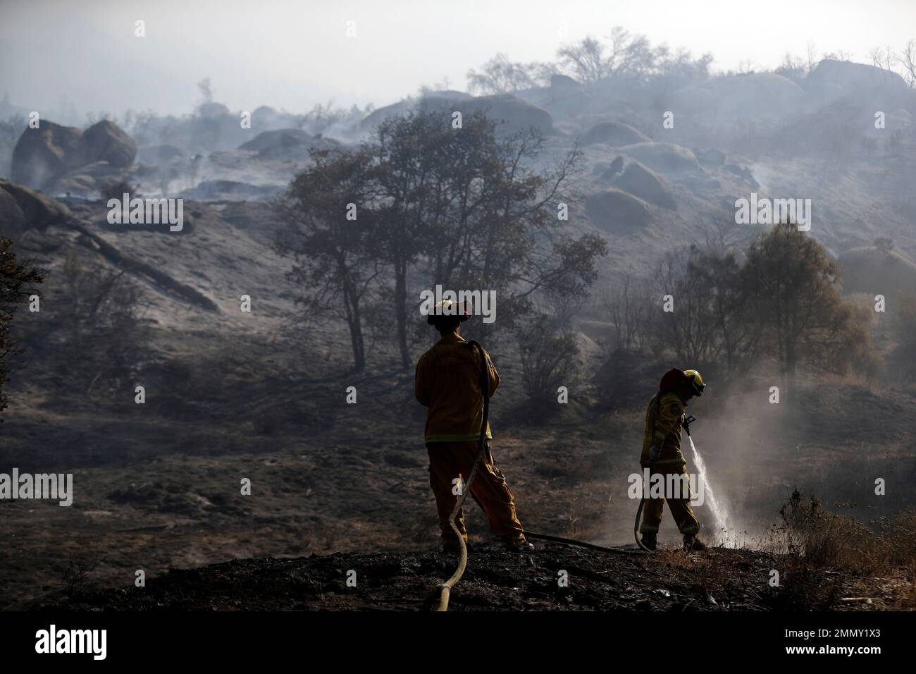 Firefighters hose down hot spots along Highway 243 on Thursday, July 26 ...
