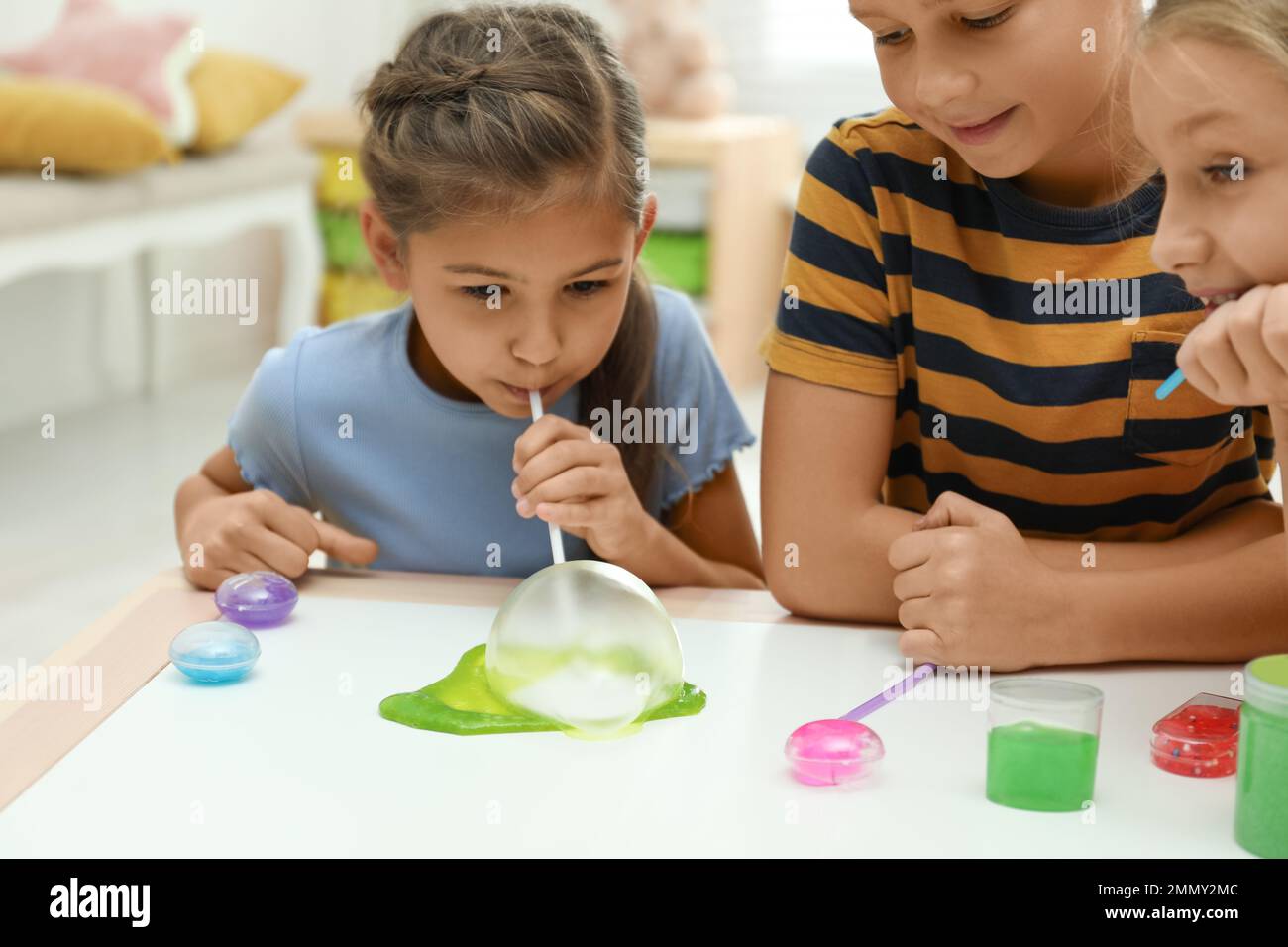 Children playing with slime at white table indoors Stock Photo - Alamy