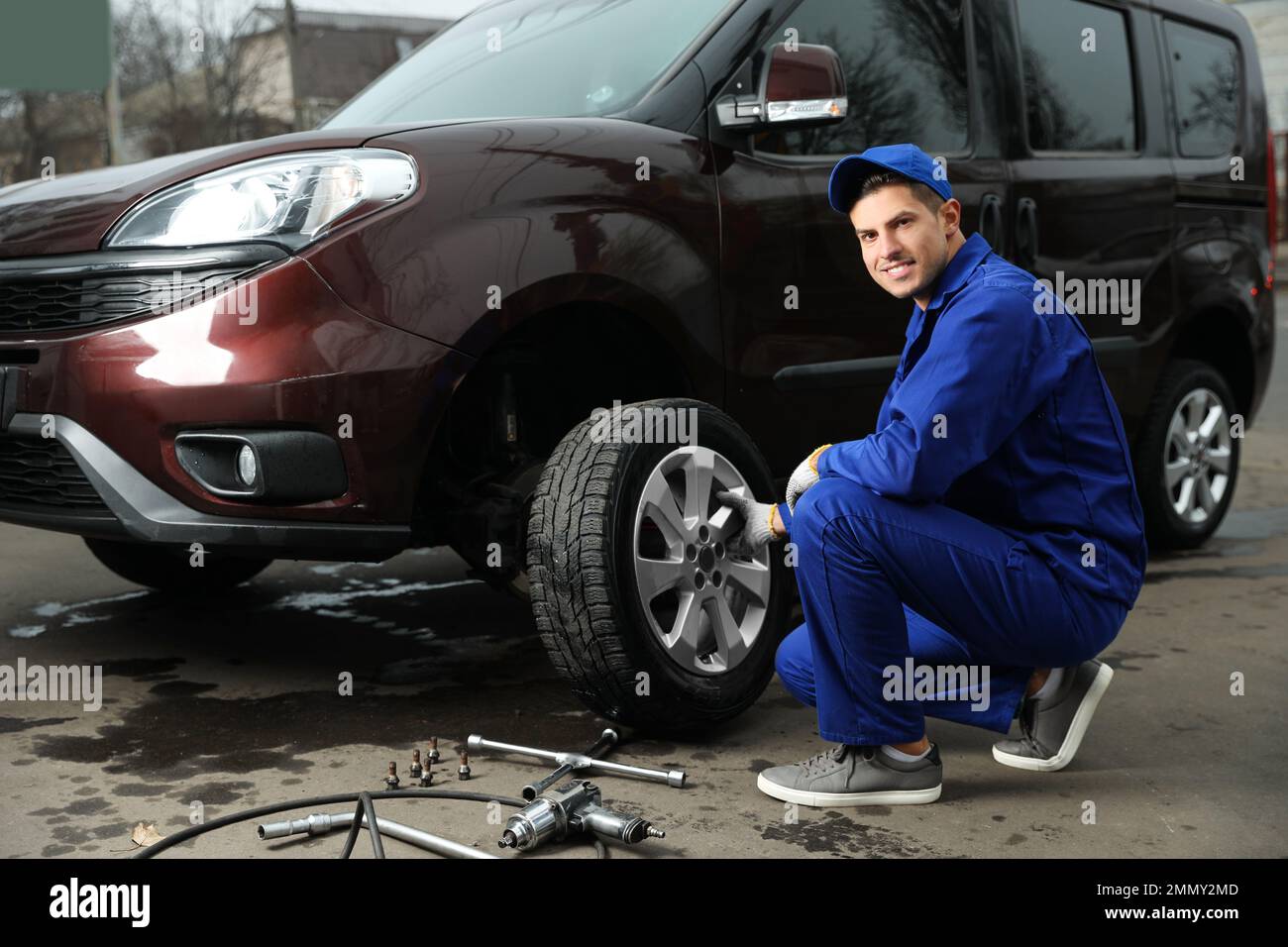 Worker changing car wheel at tire service Stock Photo - Alamy