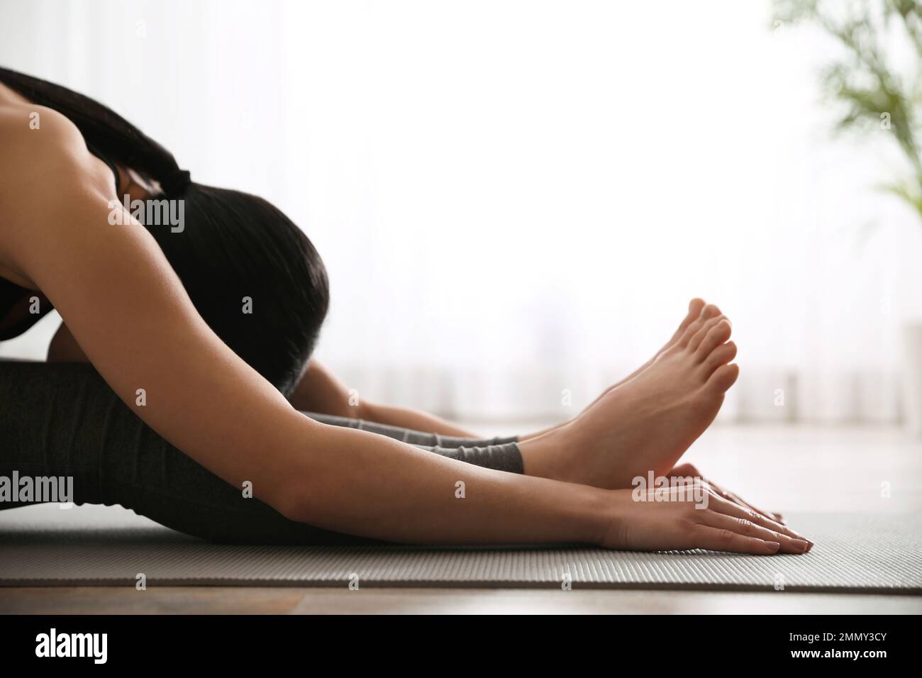 Young Woman Practicing Seated Forward Bend Asana In Yoga