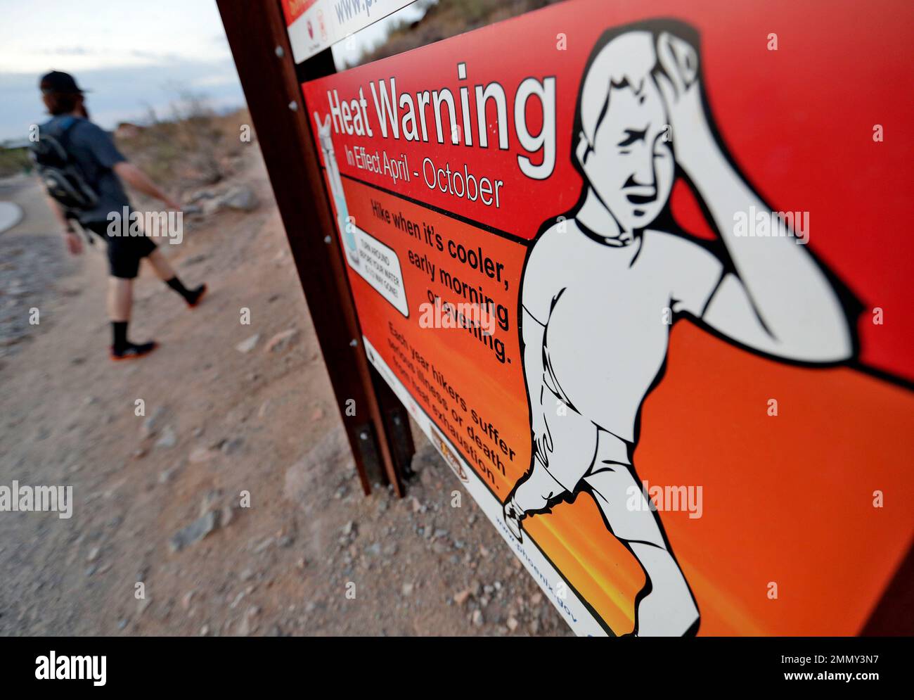 In this Tuesday, July 24, 2018 photo, a hiker walks past a heat warning ...
