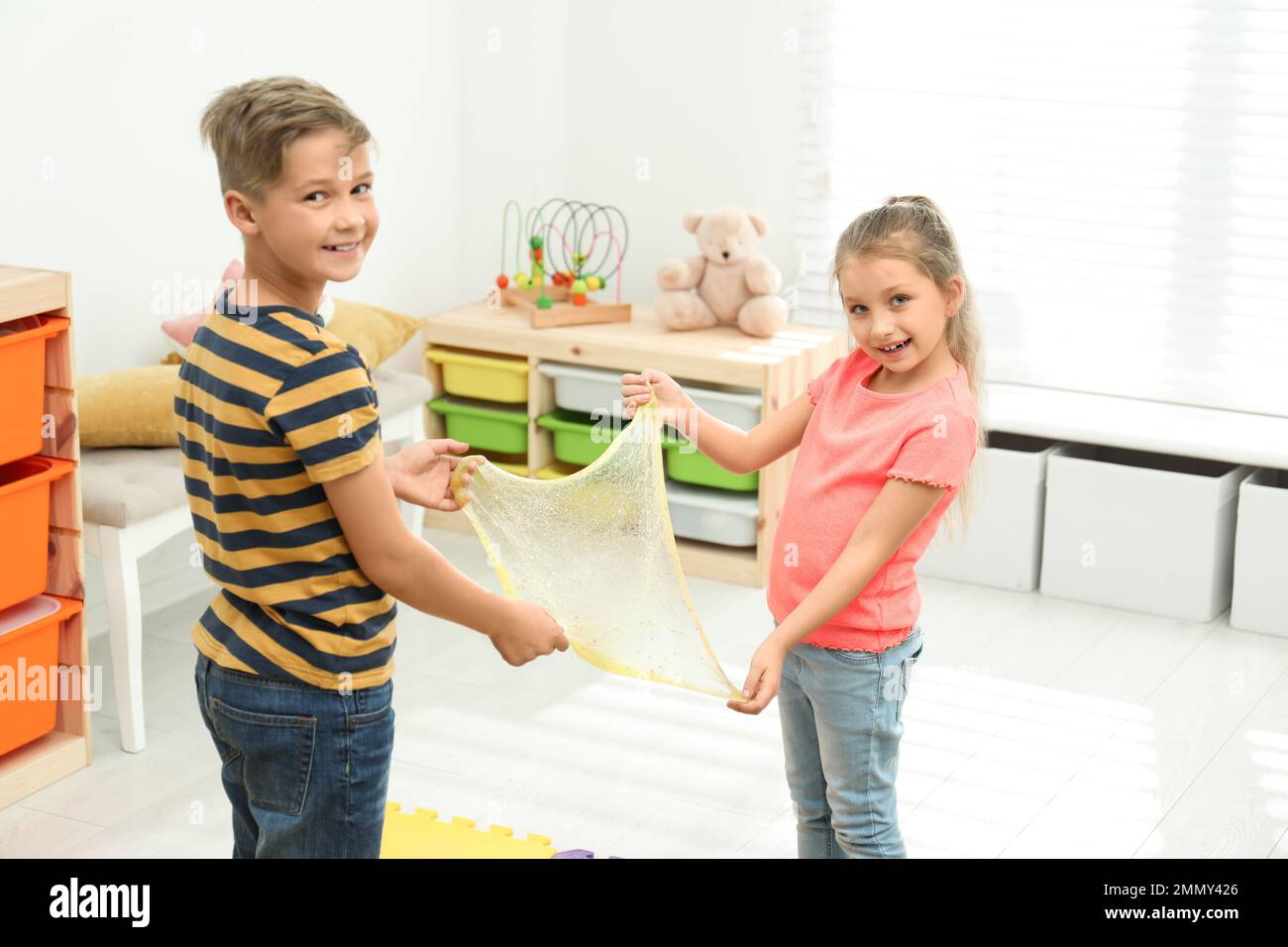 Happy children playing with slime in room Stock Photo - Alamy