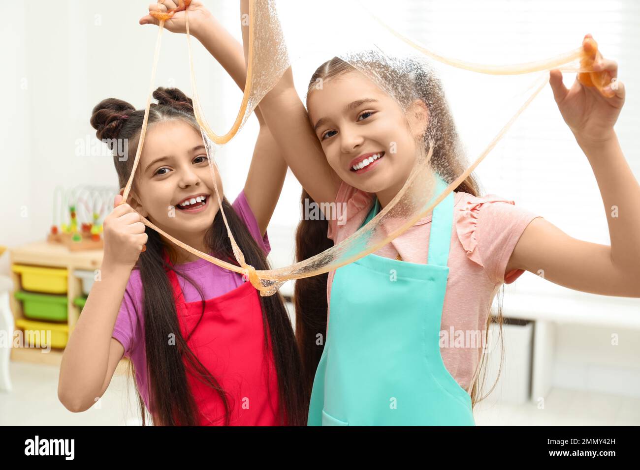 Happy girls playing with slime in room Stock Photo - Alamy
