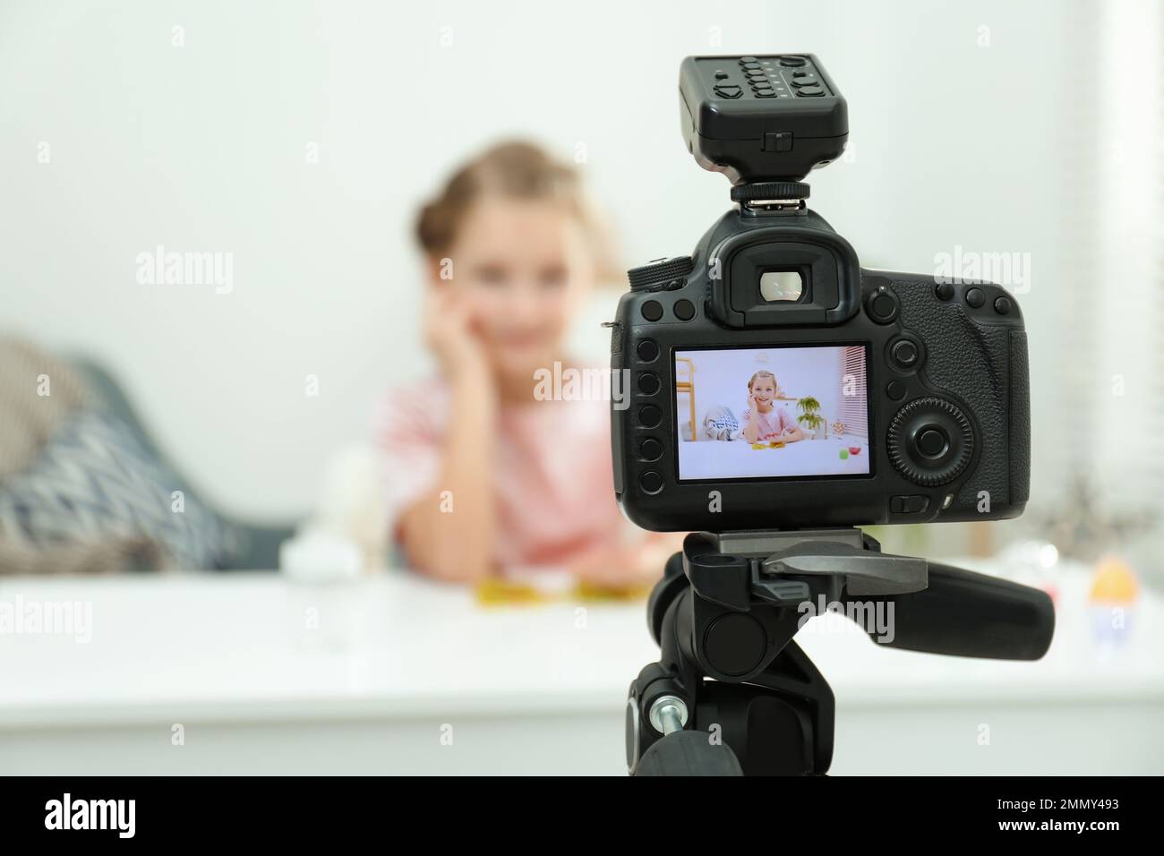 Cute little blogger with slime recording video at home, focus on camera ...