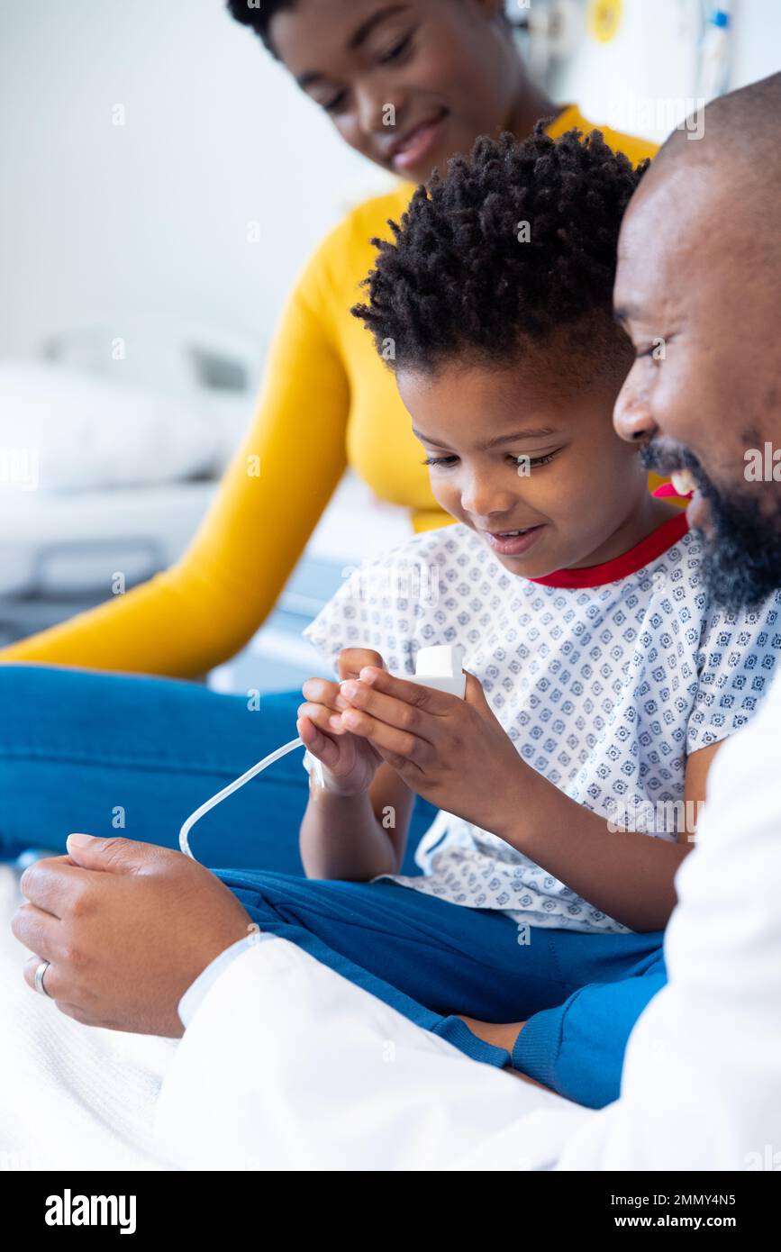 Vertical of african american male doctor showing inhaler to boy patient ...