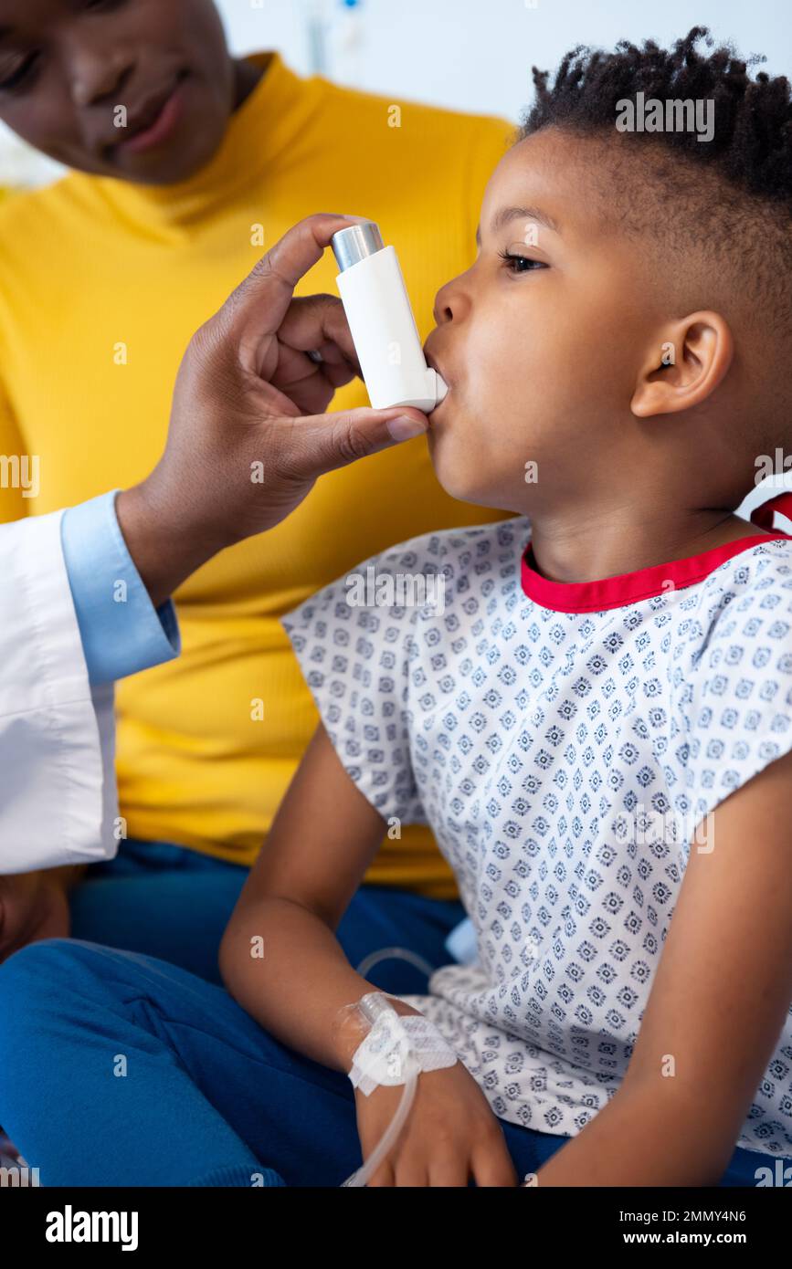 Vertical of african american male doctor giving inhaler to boy patient ...