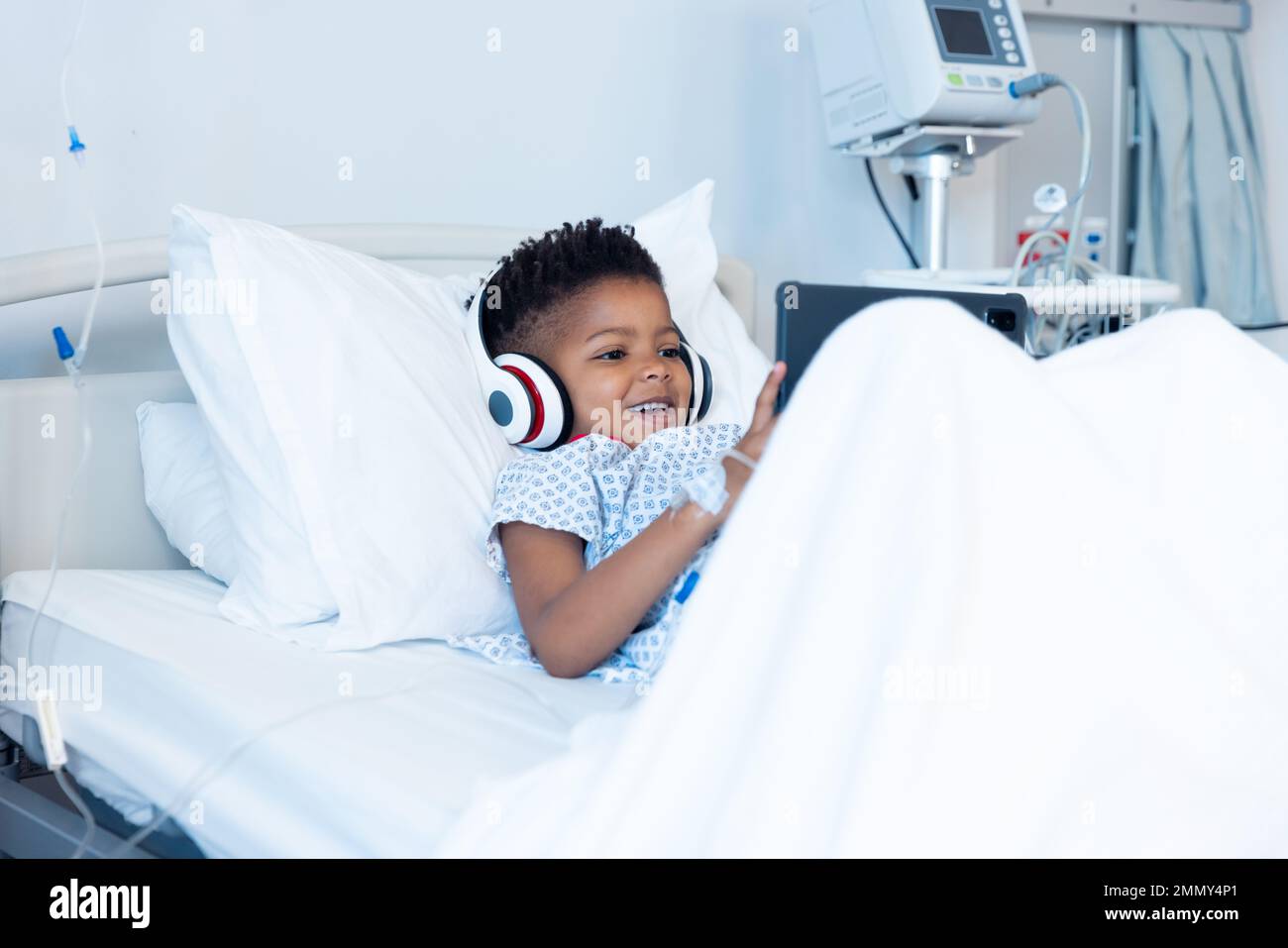 Happy african american boy patient in headphones using tablet in ...