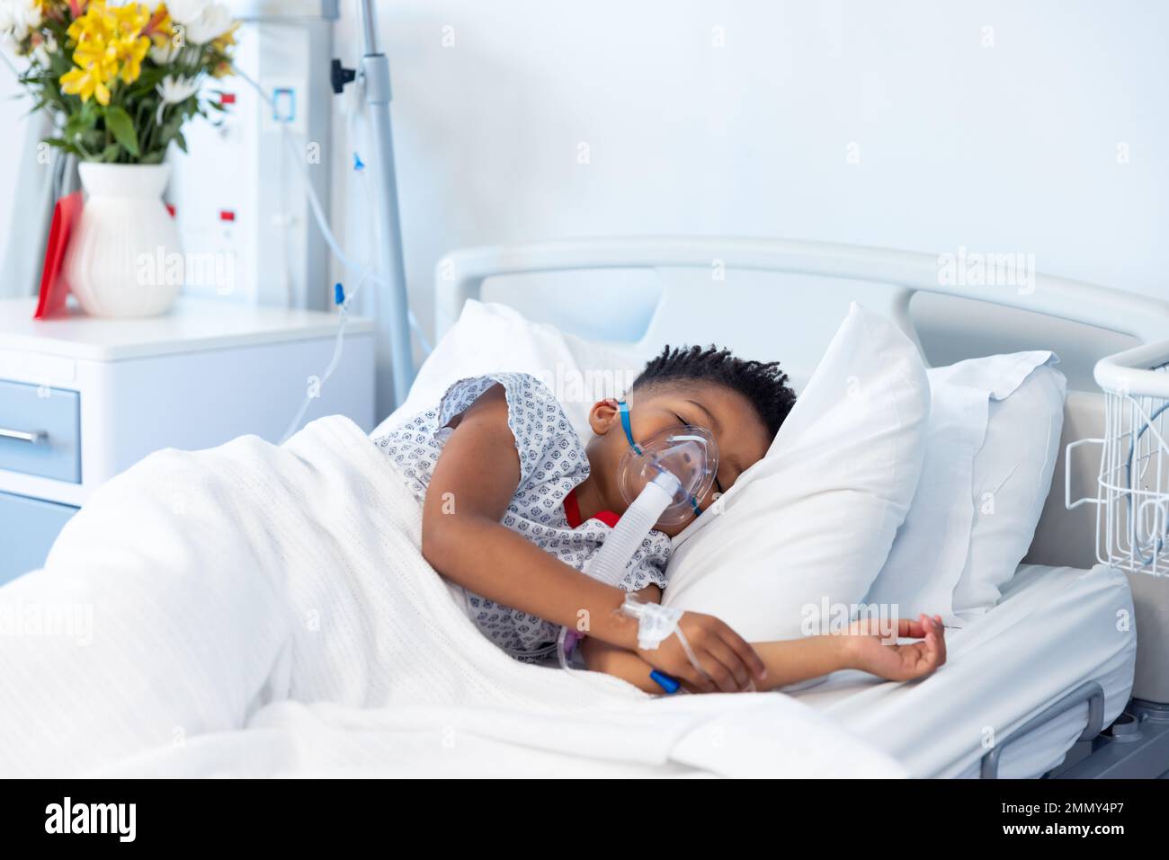 African american boy patient on ventilator asleep in hospital bed with ...