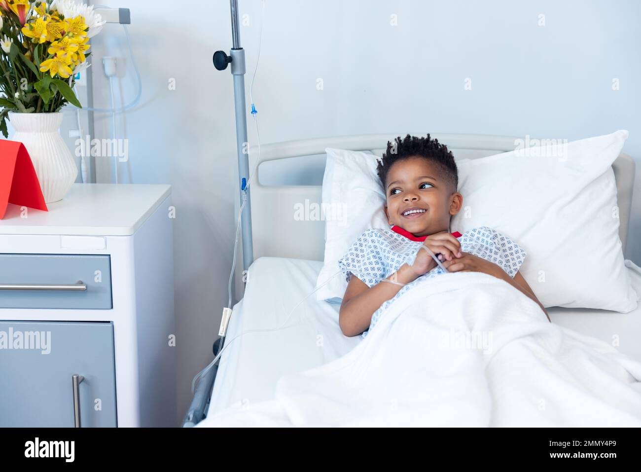 Happy african american boy patient on drip, smiling in hospital bed ...