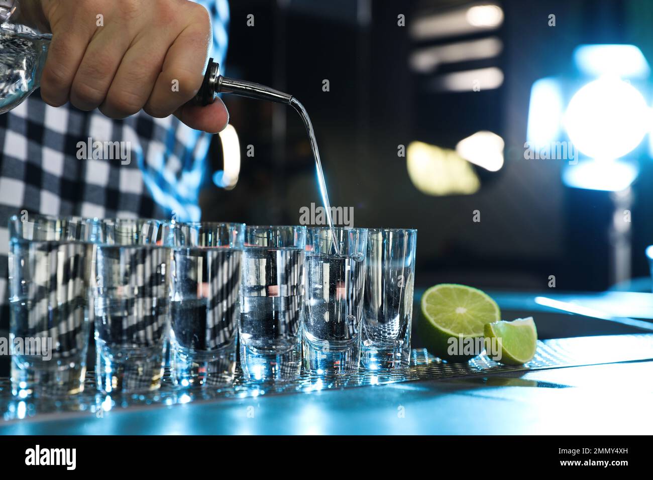 Bartender pouring Mexican Tequila into shot glasses at bar counter ...