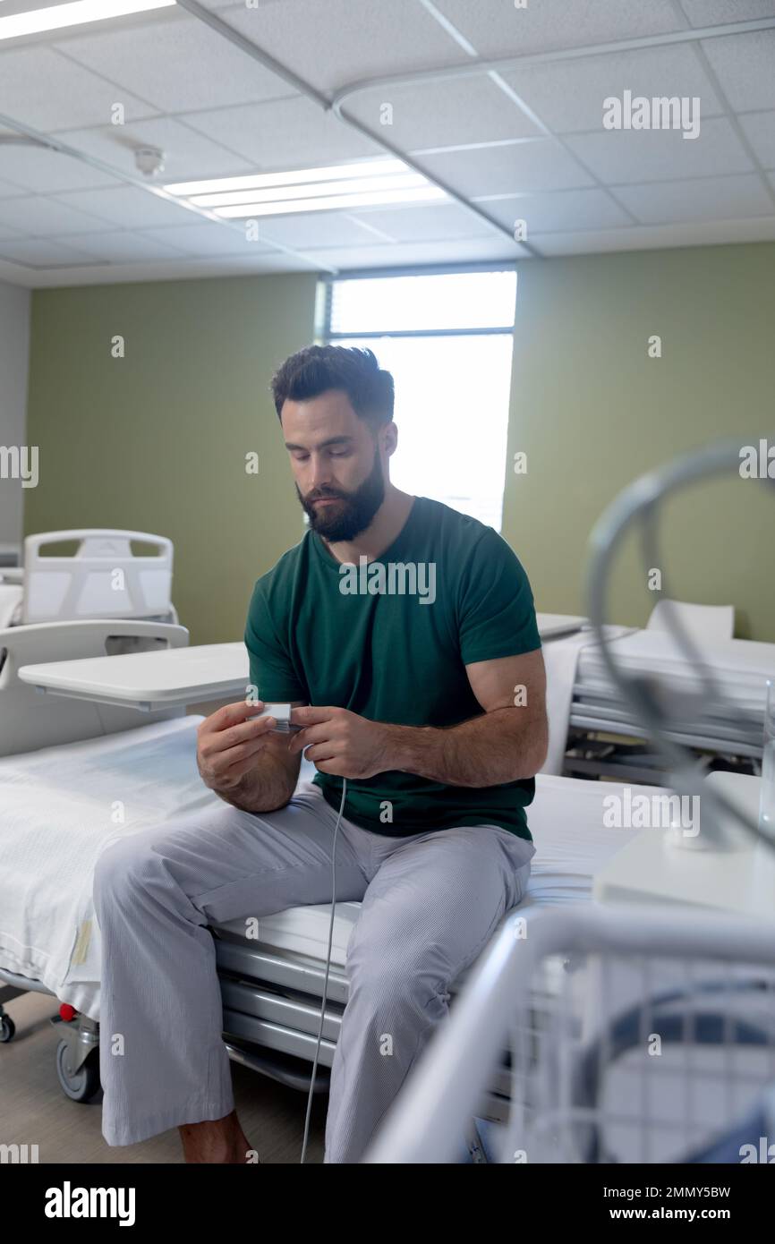 Caucasian male patient sitting on bed in room at hospital Stock Photo ...