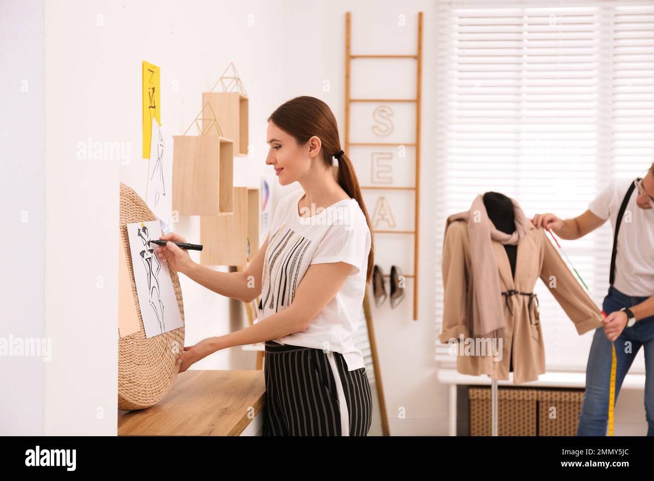 Fashion designer with colleague creating new clothes in studio Stock ...