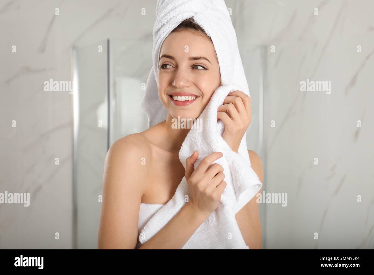 Young woman wiping face with towel in bathroom Stock Photo - Alamy