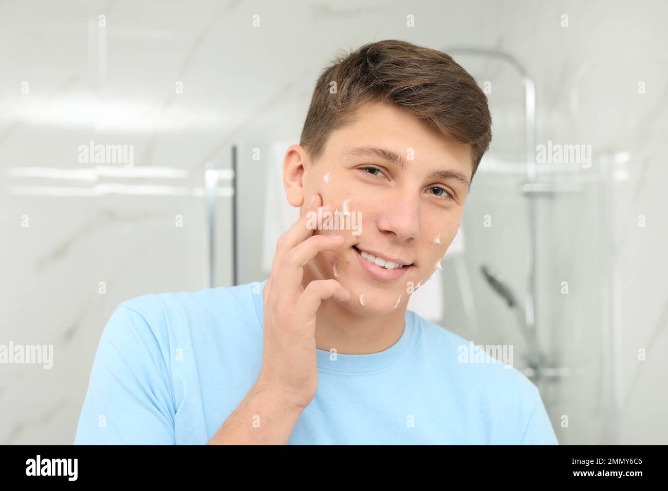 Teen guy with acne problem applying cream in bathroom Stock Photo - Alamy
