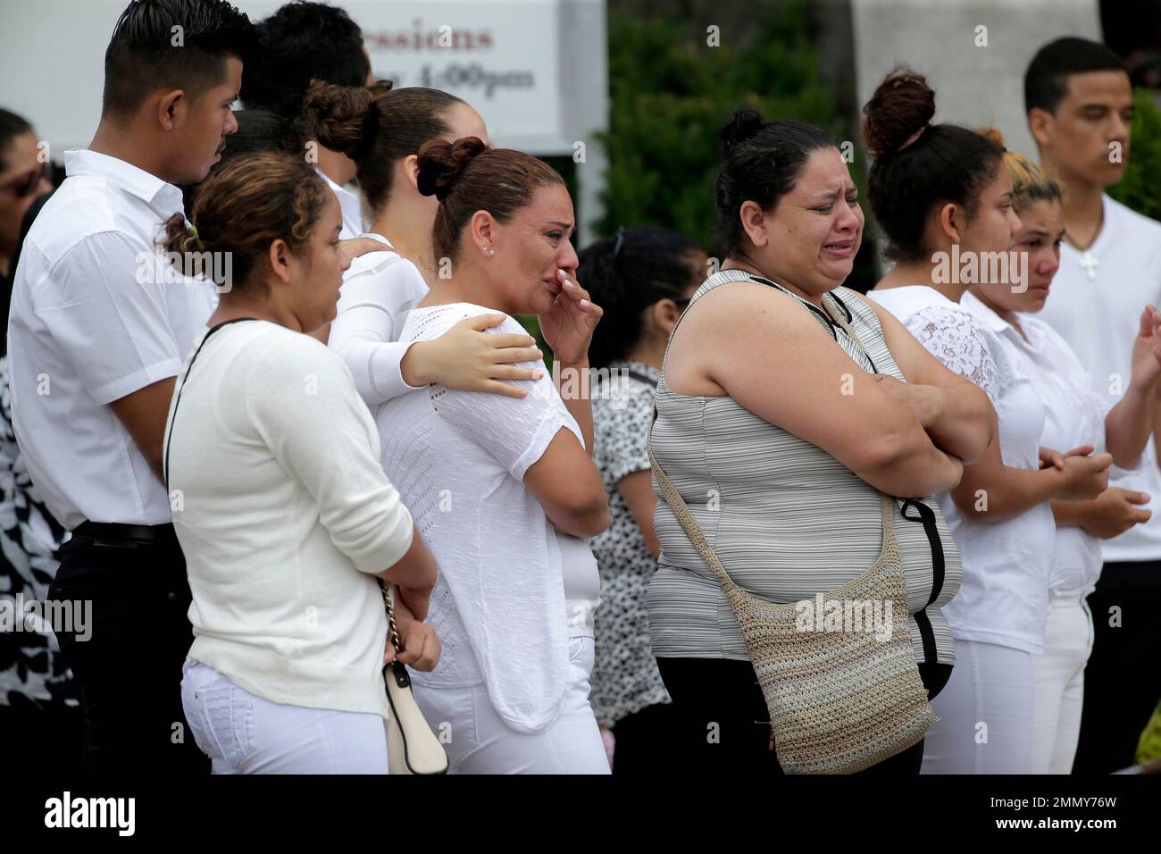 People cry and become emotional as five caskets are loaded into hearses ...