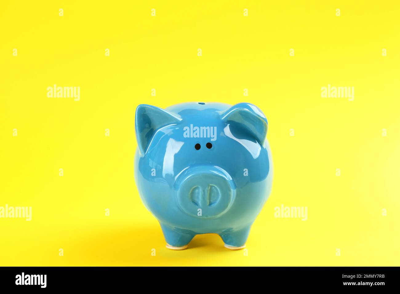 Cute blue piggy bank on yellow background Stock Photo - Alamy