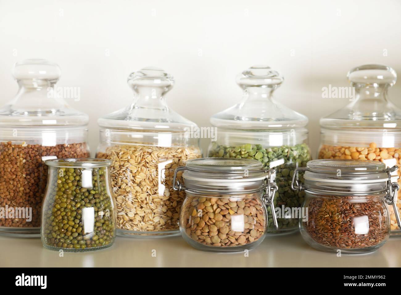 Different types of legumes and cereals in jars on table. Organic grains Stock Photo - Alamy