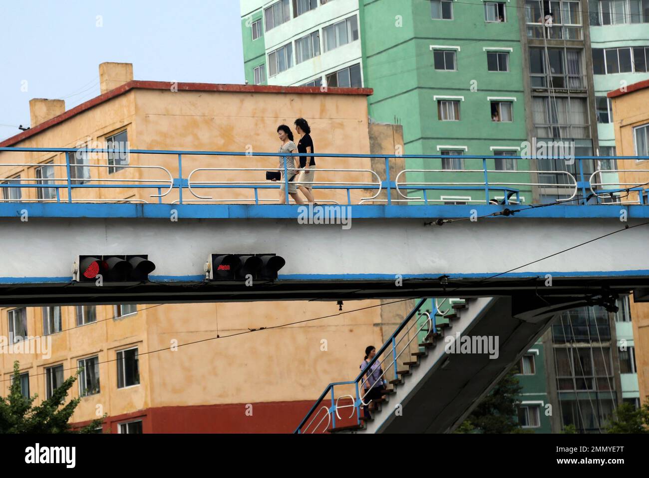 Women cross a pedestrian bridge in a residential area of downtown ...