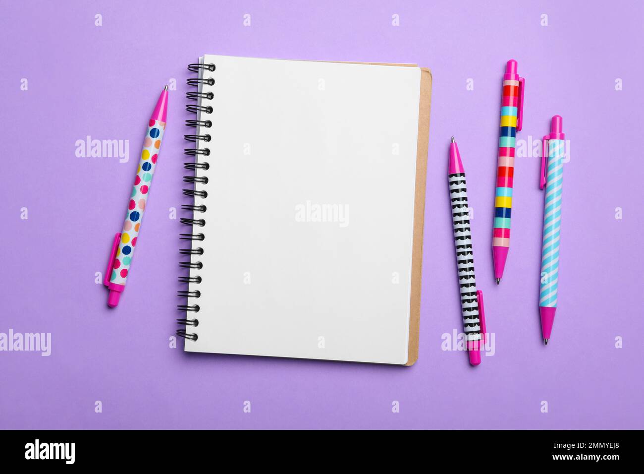Open notebook and pens on lilac background, flat lay Stock Photo - Alamy