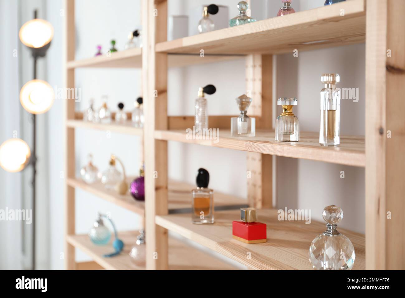 Different perfume bottles on wooden rack indoors Stock Photo - Alamy