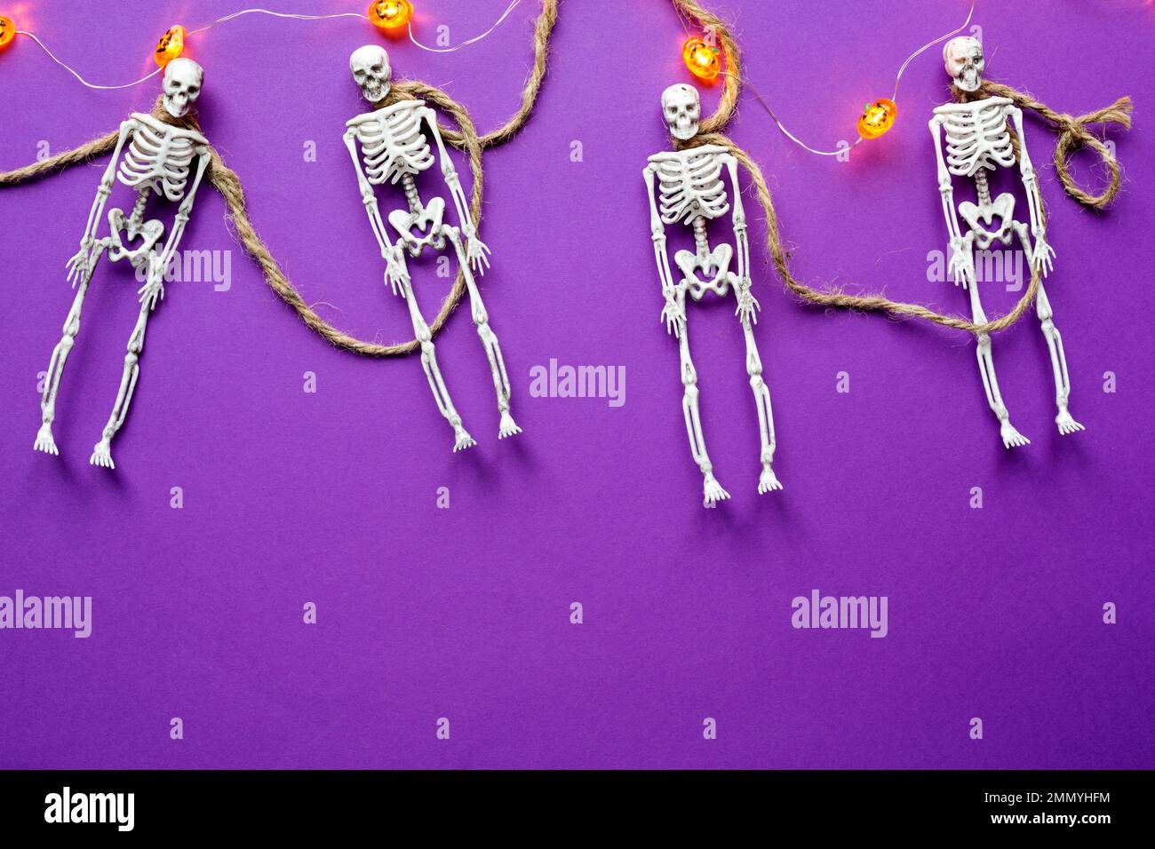 Halloween layout of garland of skeletons on a rope, glowing Jack o ...
