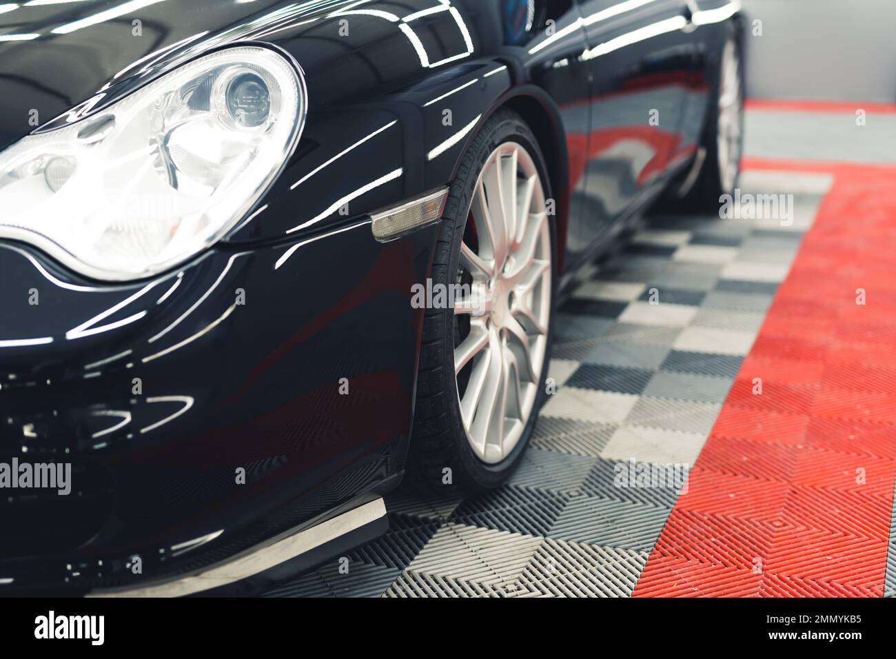 Back view of a shiny black sports car at car detailing salon. Low angle ...