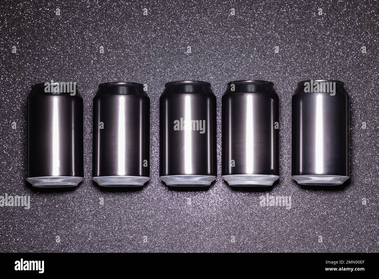 Photo of five black blank aluminium cans in a row with hard lighting on ...