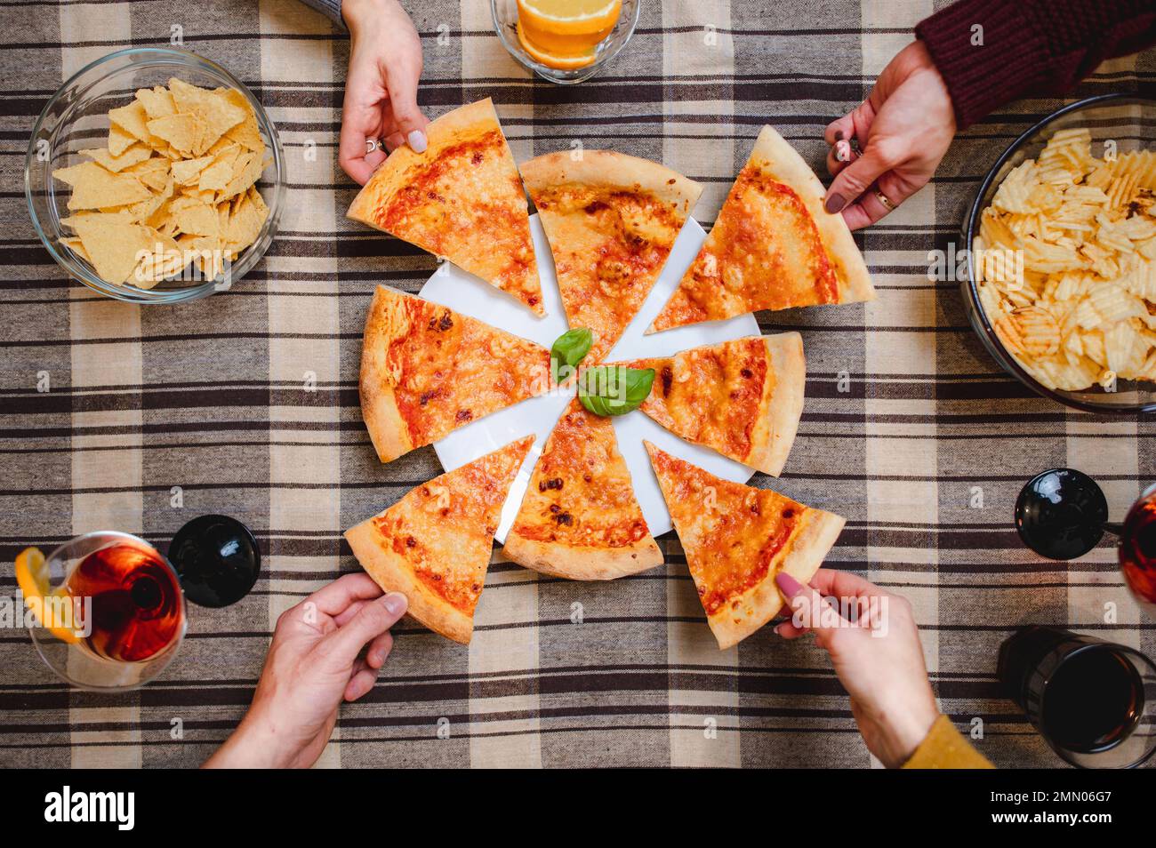 Top view of crop unrecognizable friends gathering at table and eating ...