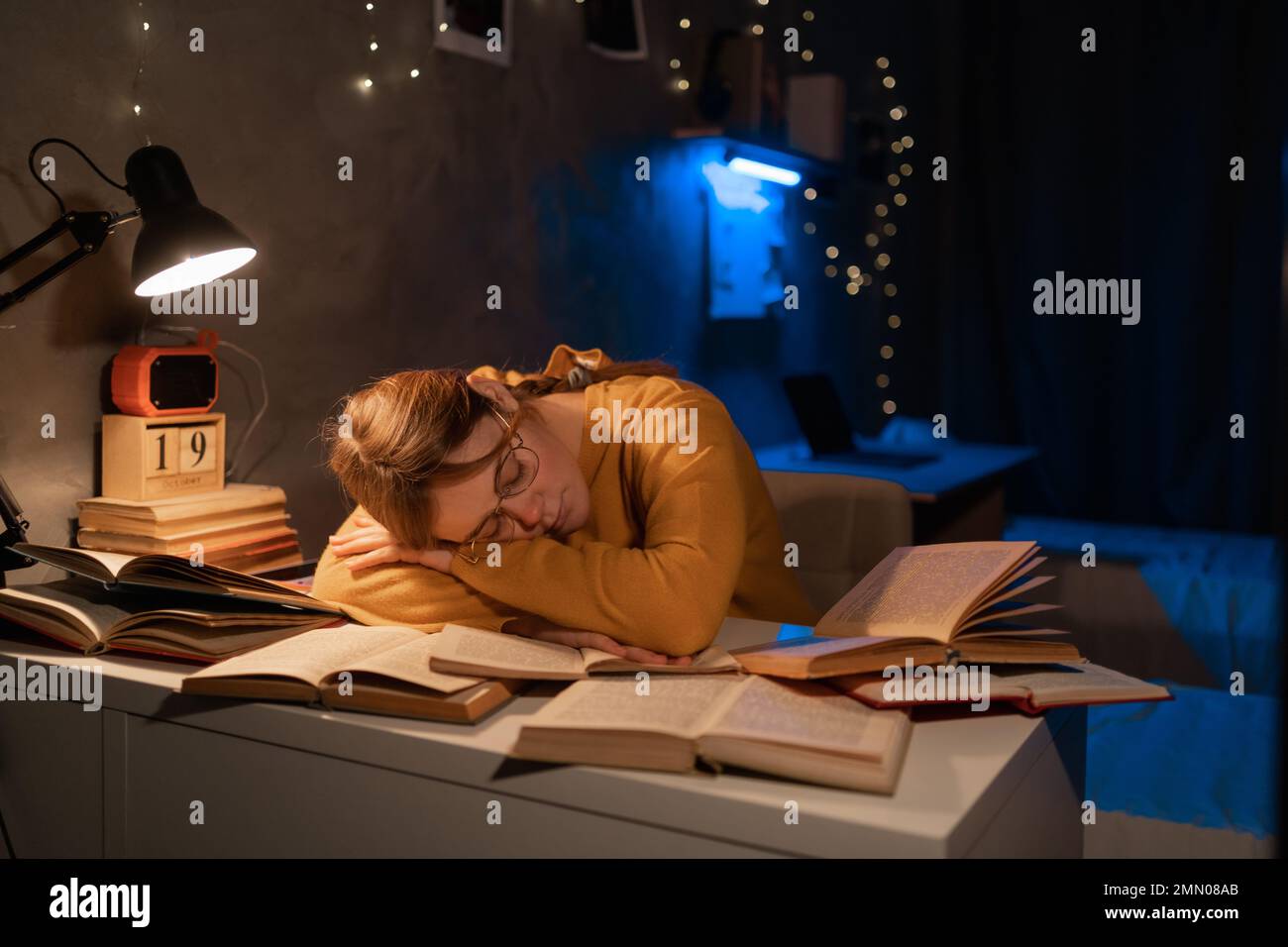 Tired college student sleeping at table in dormitory preparing for ...