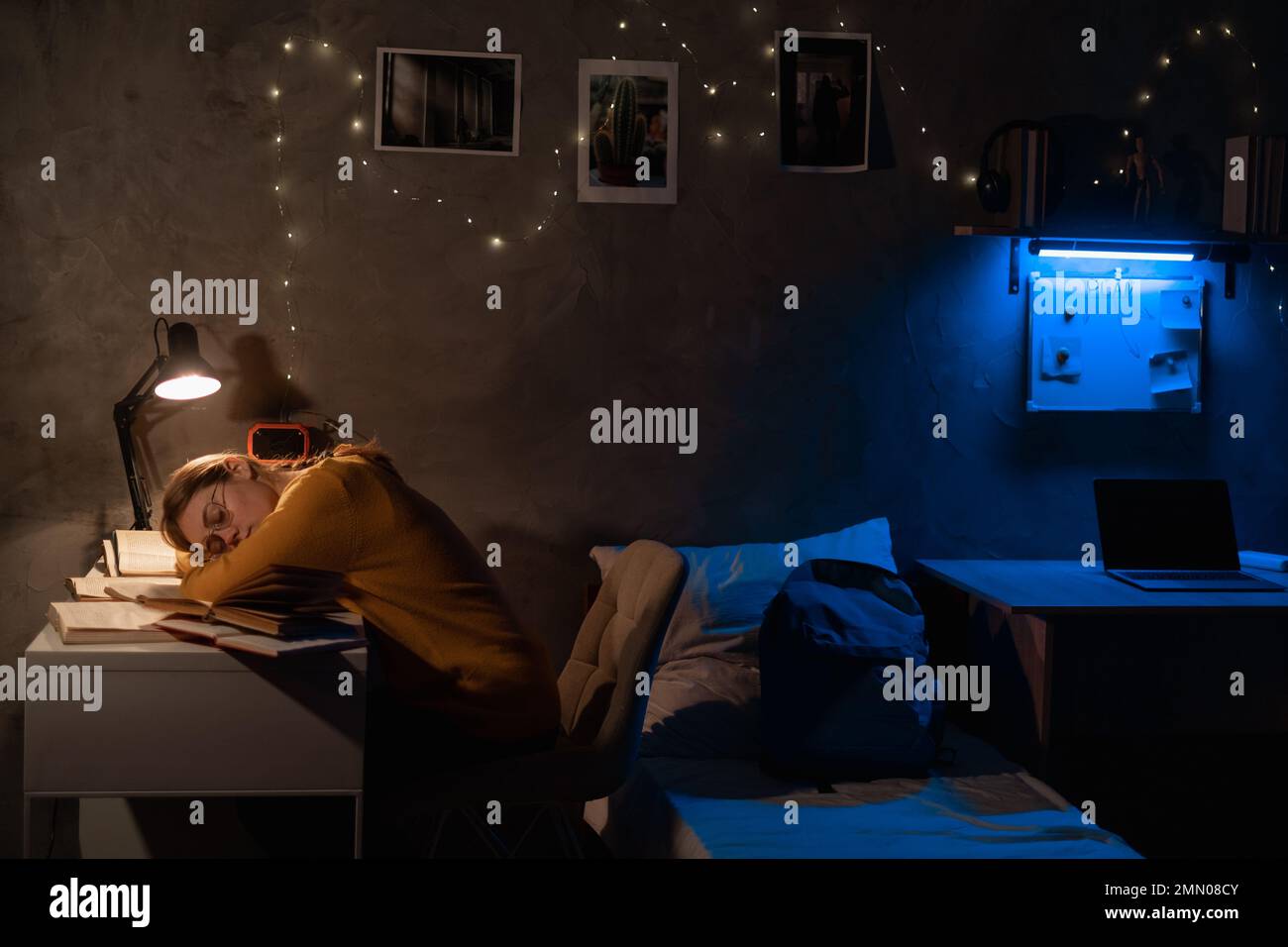 Tired college student sleeping at table in dormitory preparing for exam ...