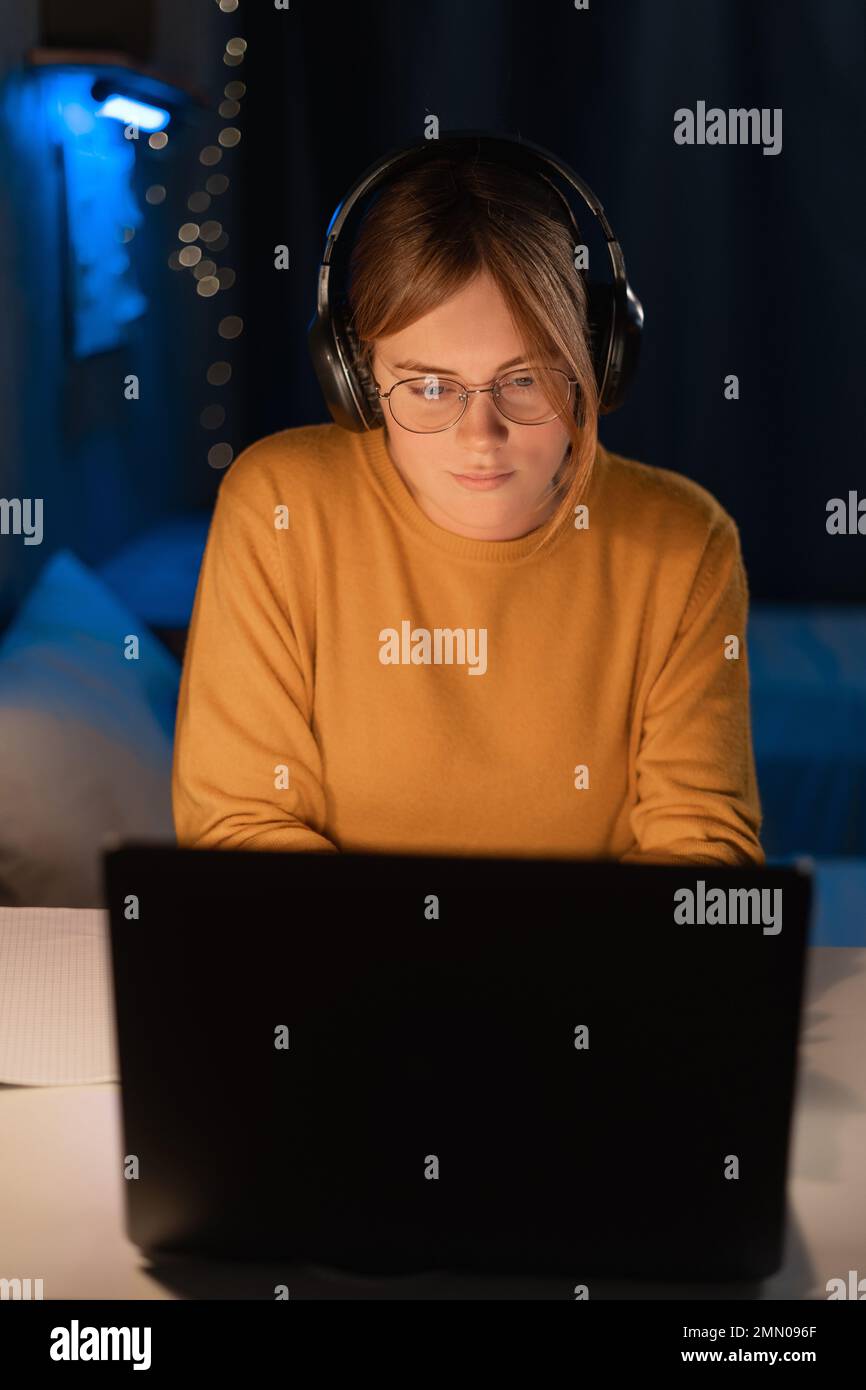 Young intelligent woman student wearing sweater works on her laptop in ...