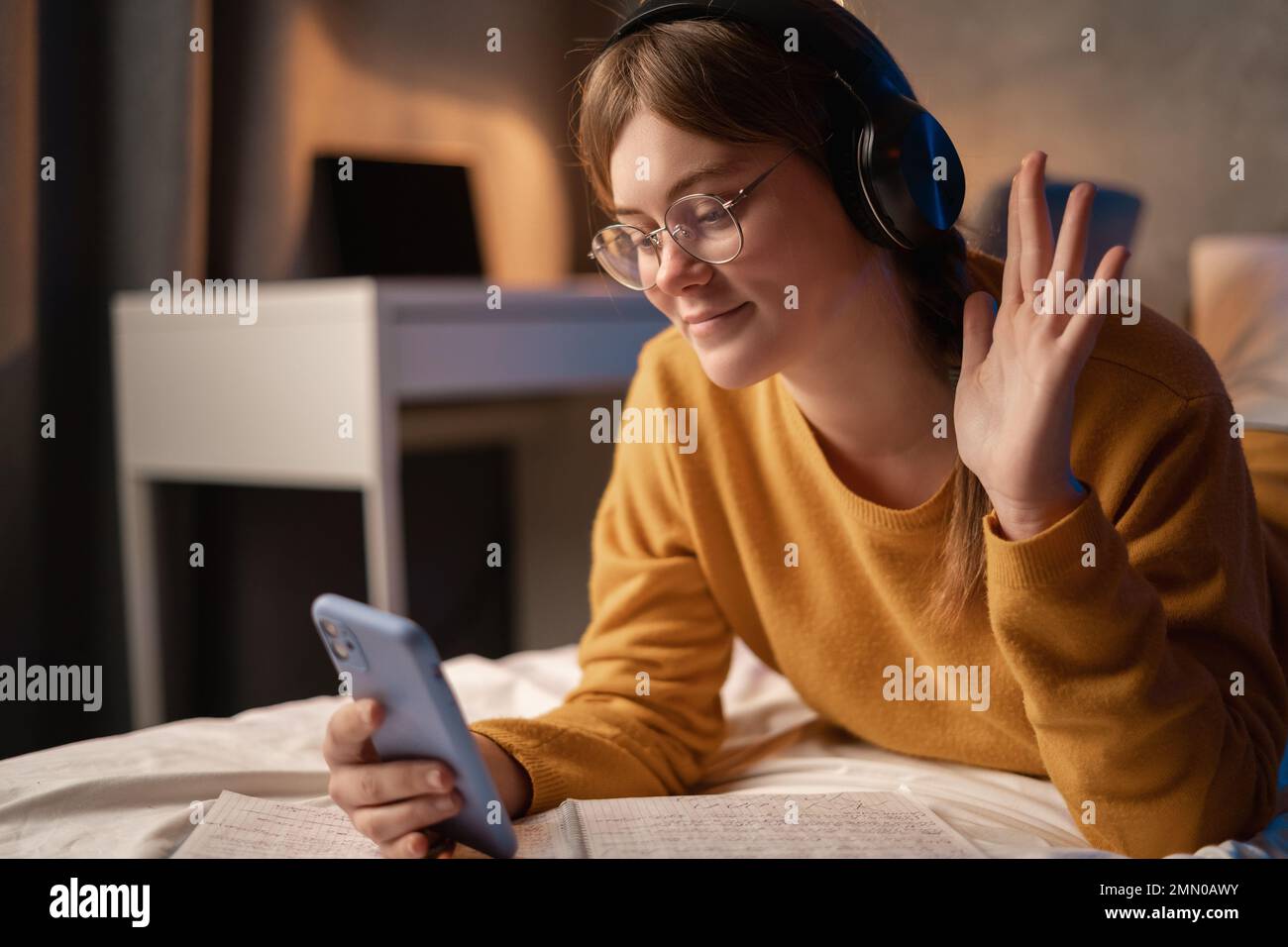 Teen girl having video chat with friends using phone camera while lying ...