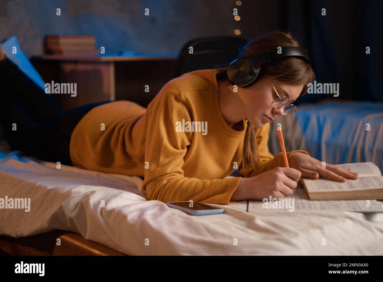 Female university or college student studying with textbooks on bed in ...