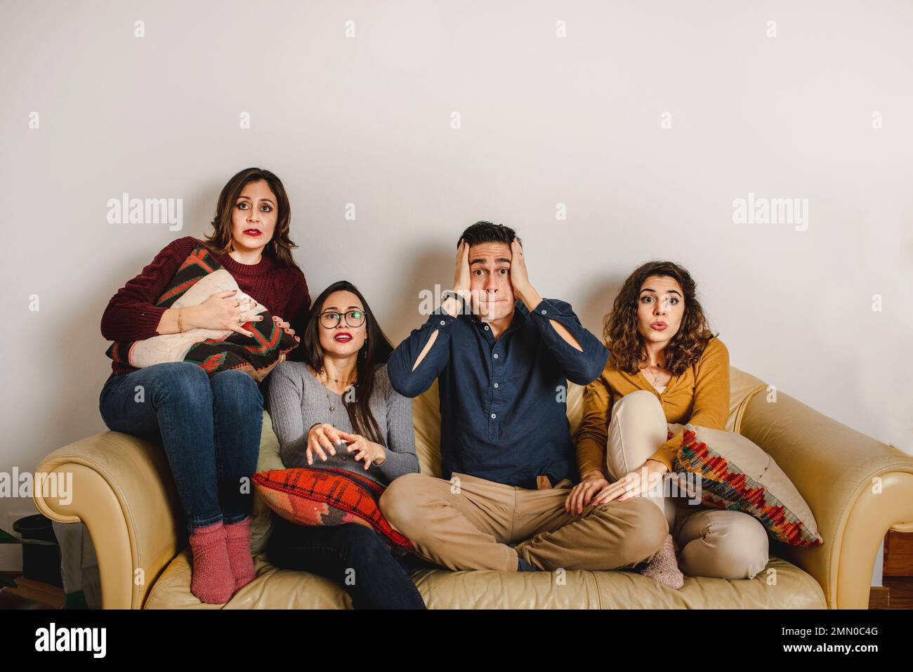 Group of scared friends gathering on sofa and watching horror movie ...