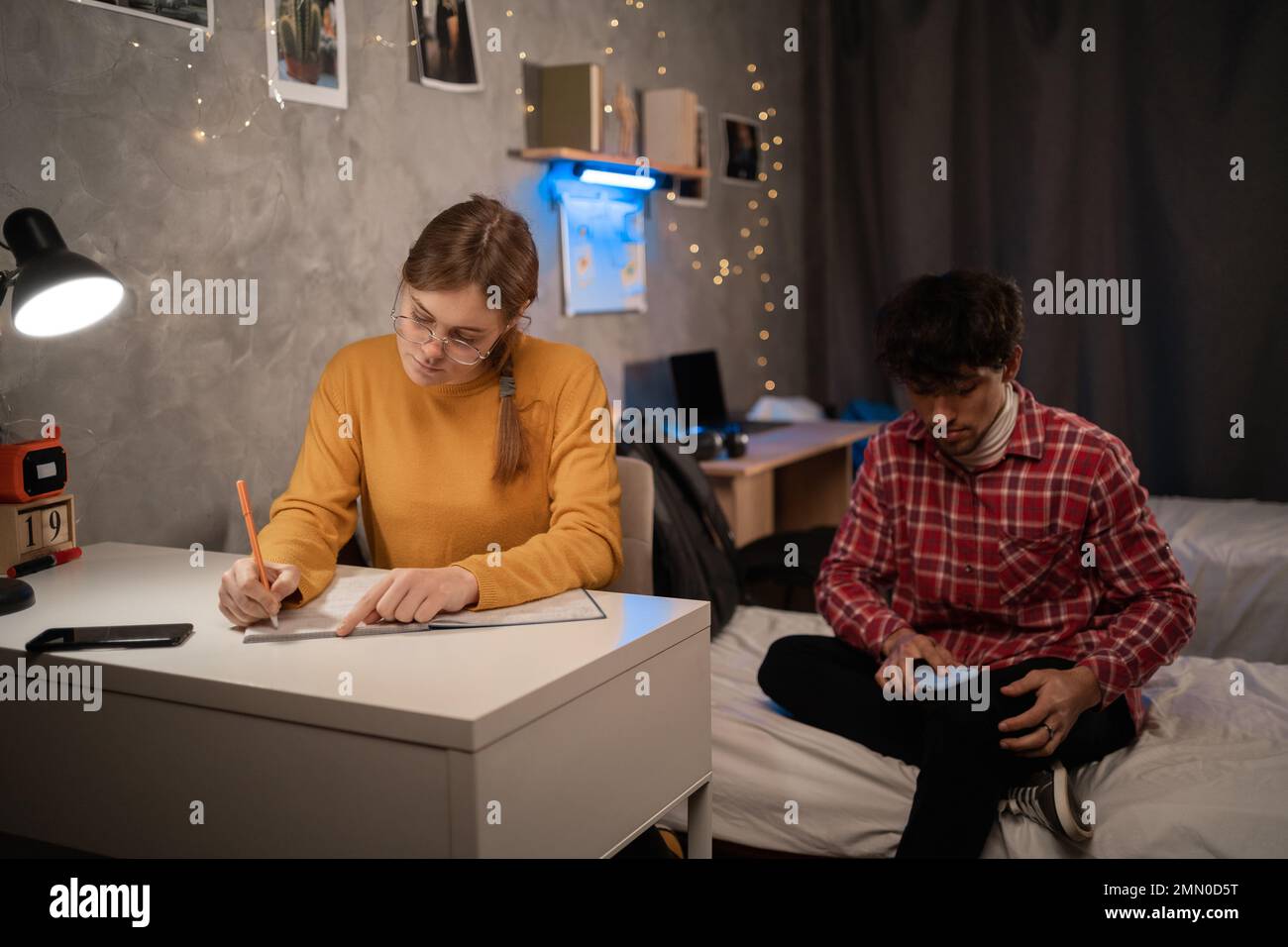 Serious female and male college students studying in dormitory at night ...