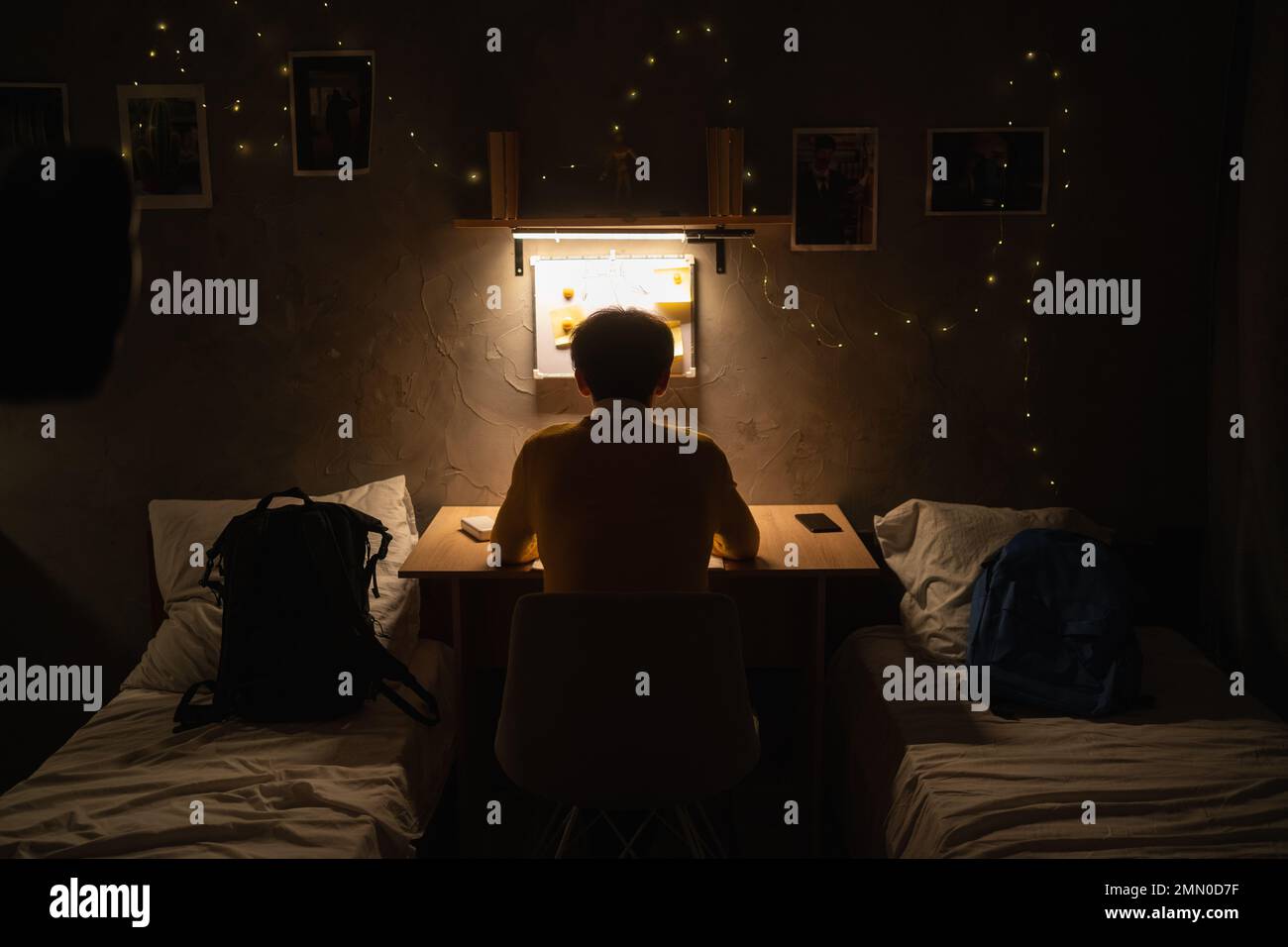 Late night study sessions. Back view of a young student studying late ...